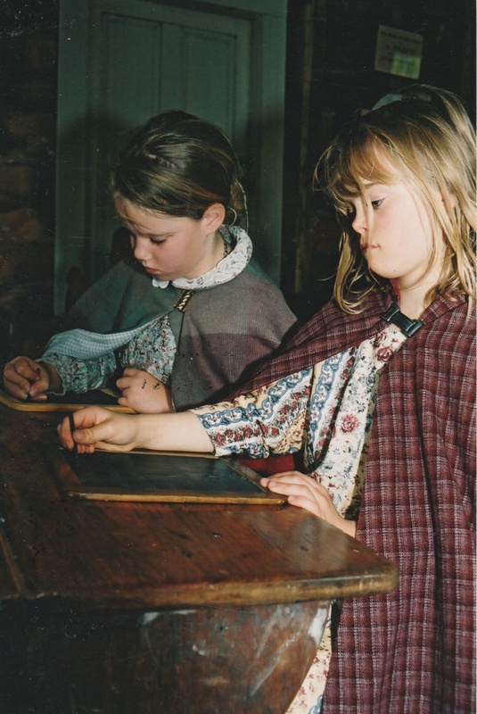 Two girls writing with slates, at their desks in Ararimu Valley School ...