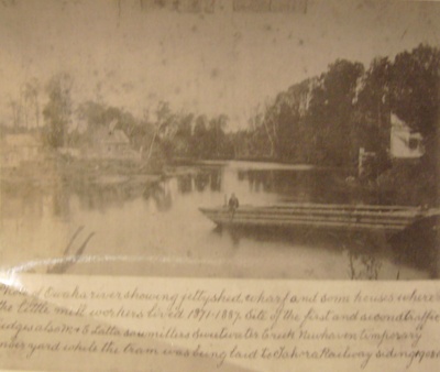 Photograph: Owaka River with boat in foreground, jetty shed and two ...