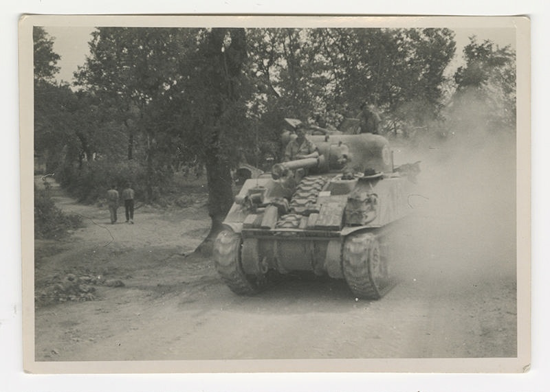 Photograph of a Sherman tank travelling down a dusty road. 1944.; John ...