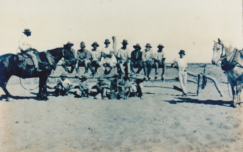 Group of stockmen, standing and mounted, on and in front of post and ...