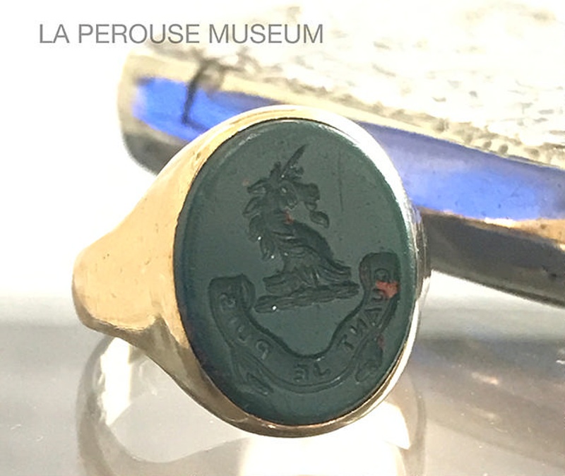 A gold signet ring with a green stone engraved with a bearded unicorn ...