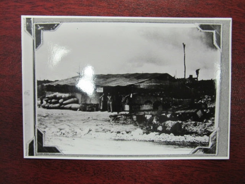 Photograph of soldiers standing in front of the entrance to a run down ...