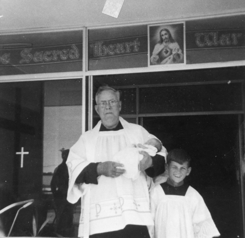 Father Vince Ashwood holding baby Amanda Sladden with altar boy Patrick ...