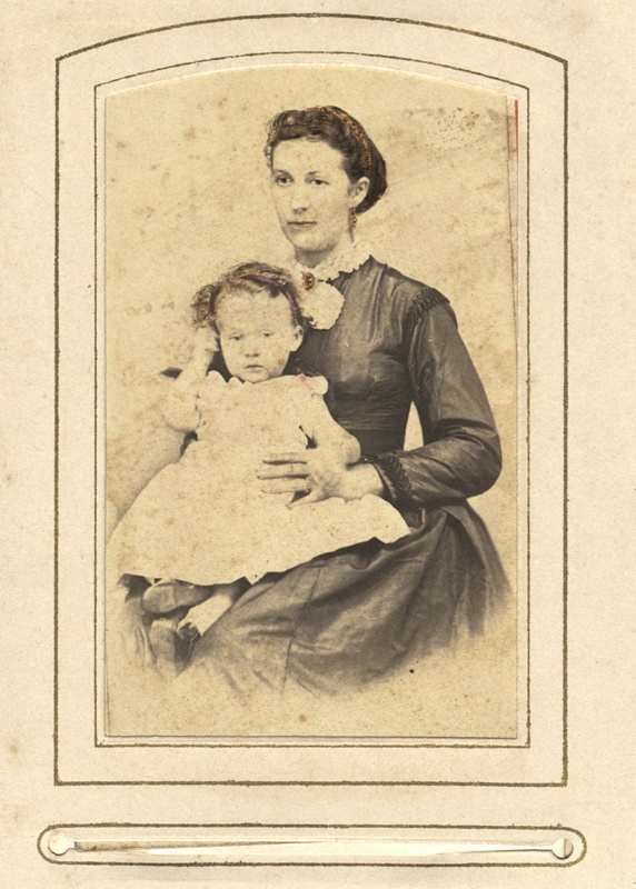 Studio photo of a baby girl sitting on her mother's lap.; J.Hubert ...