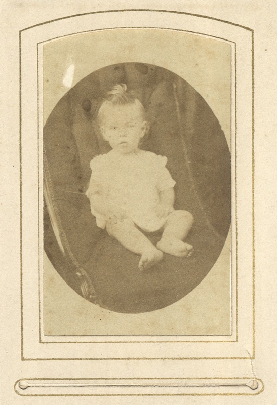 Studio photo of a baby with spiked hair style seated on a chair.; J ...