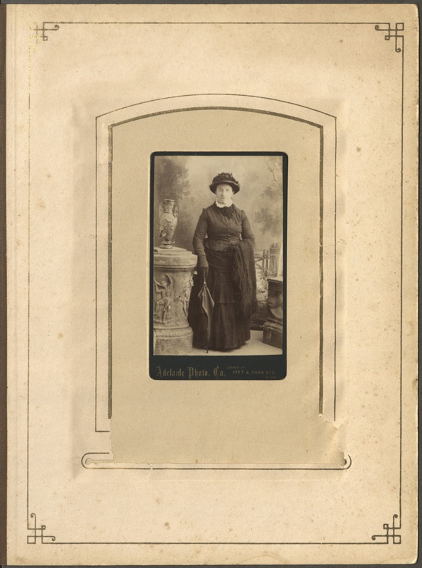 Studio photo of a hatted lady in formal attire standing with folded ...