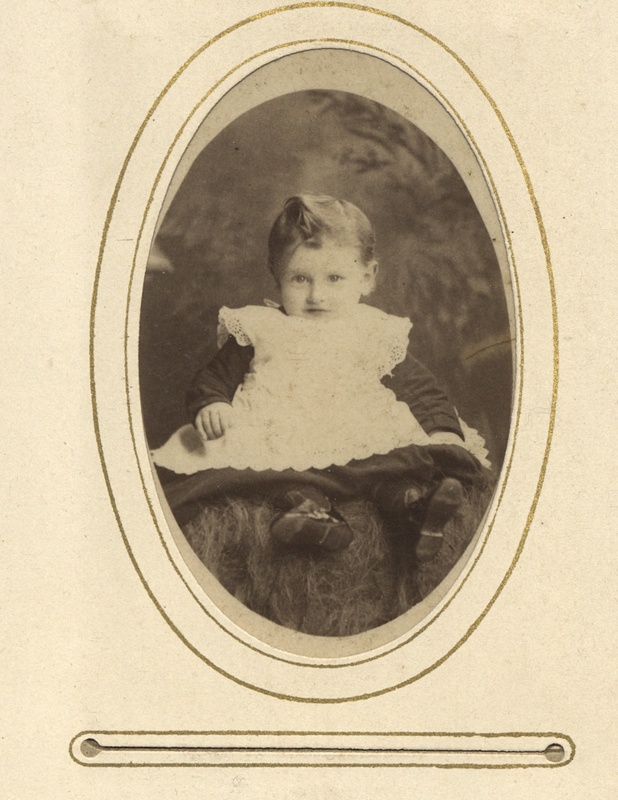 Studio photo of a baby girl wearing a white crocheted smock.; J.Hubert ...
