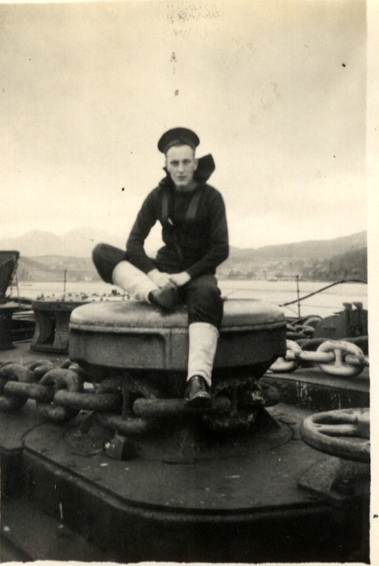 Photograph of an unidentified naval rating sitting on the capstan of an ...