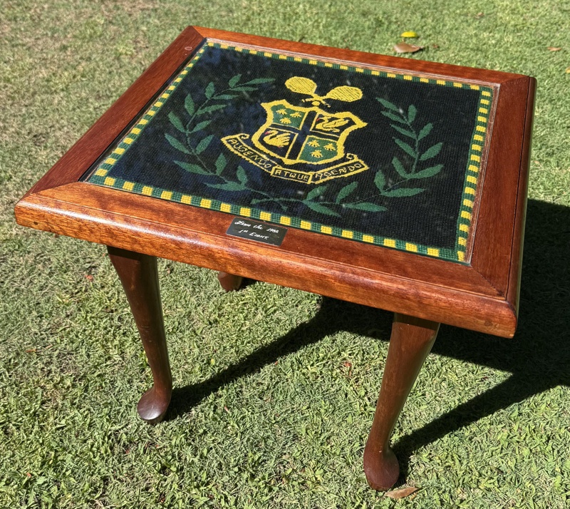 Small table with glass top containing Wesley crest 1982; Donated by ...
